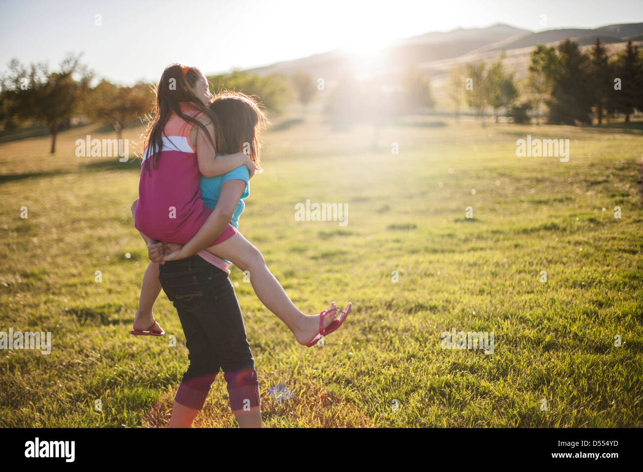 Girl carrying friend piggyback in field Stock Photo - Alamy Girl carrying friend piggyback in field Stock Photo - Alamy