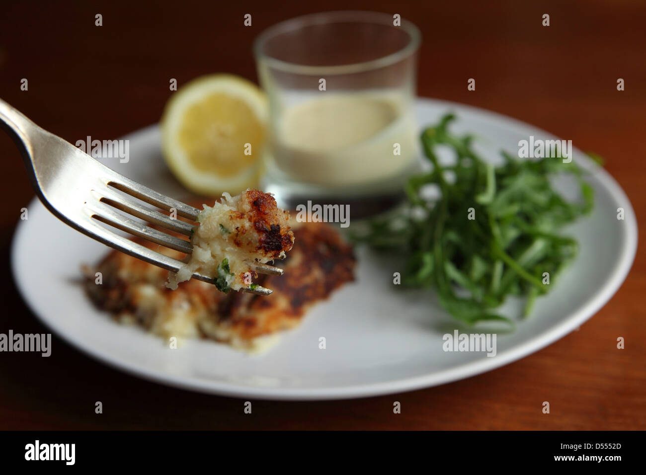 Fish cake served with a wedge of lemon, rocket (ruccola) salad and ...