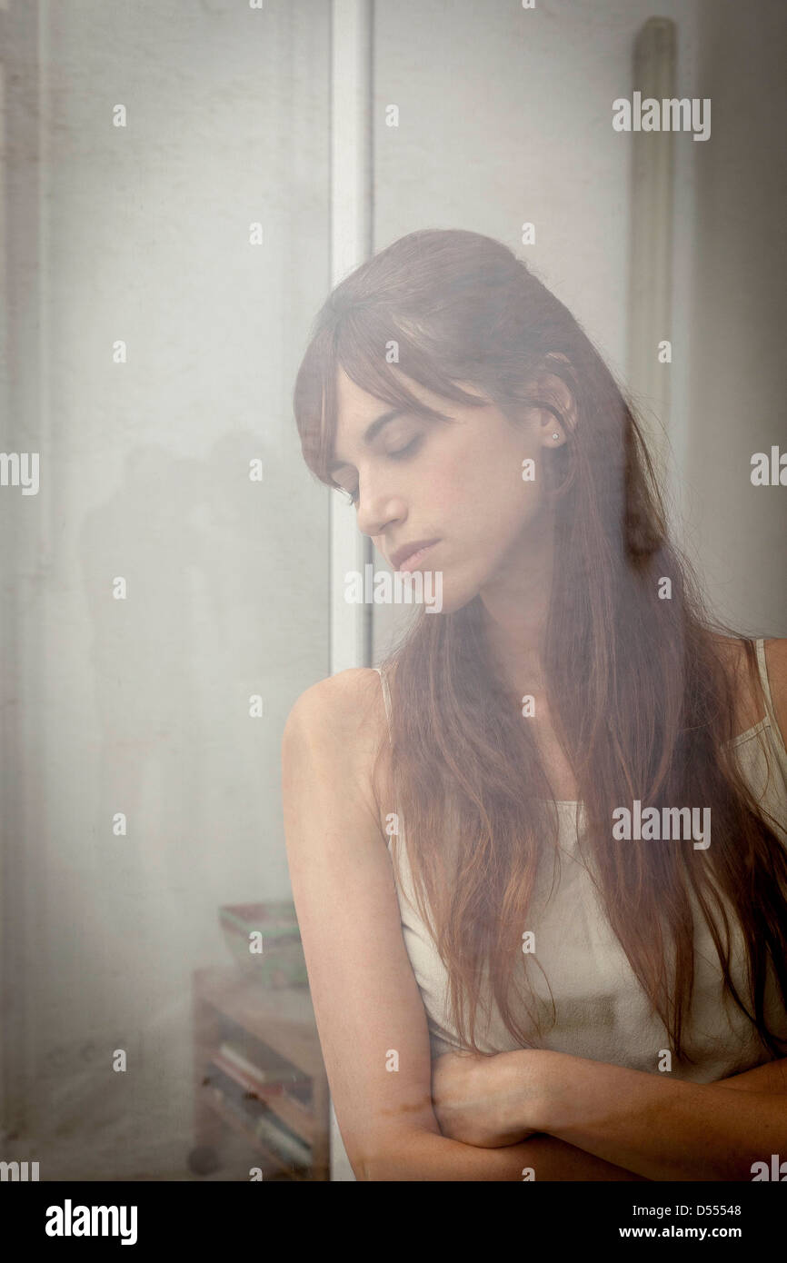 Sad woman standing at window Stock Photo - Alamy