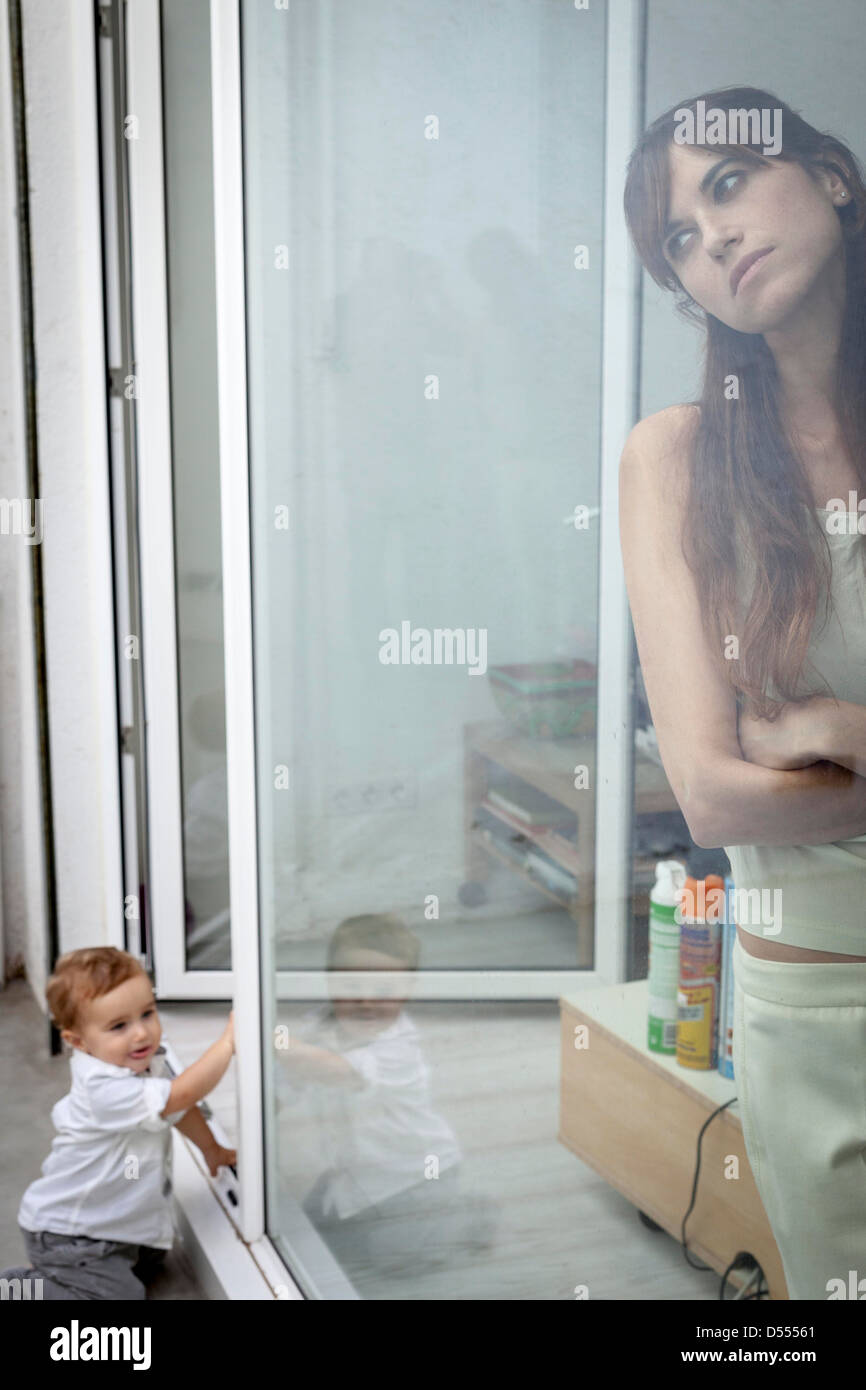 Boy watching mother look out window Stock Photo - Alamy