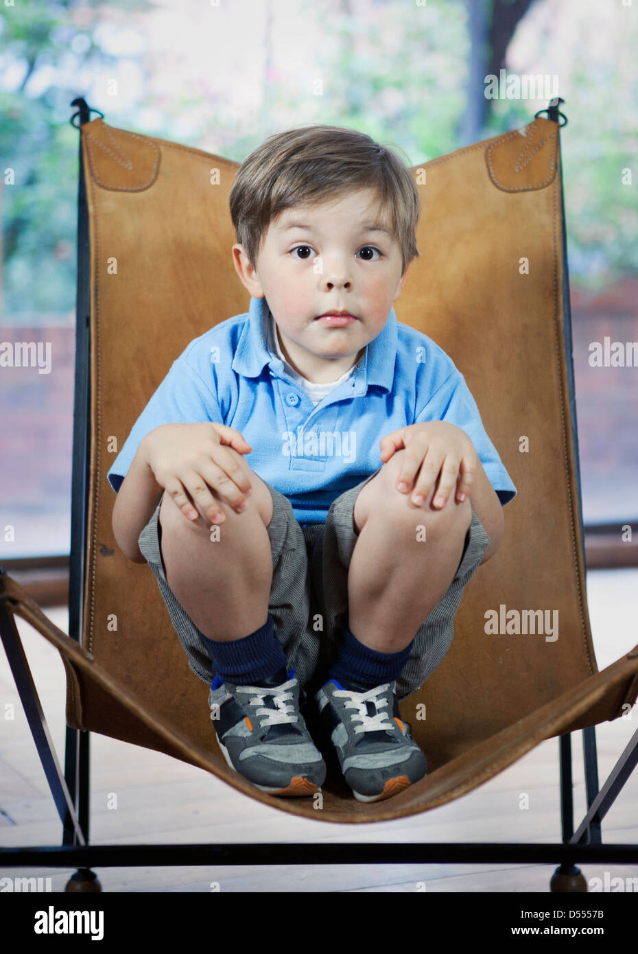 Boy crouching in camp chair Stock Photo - Alamy