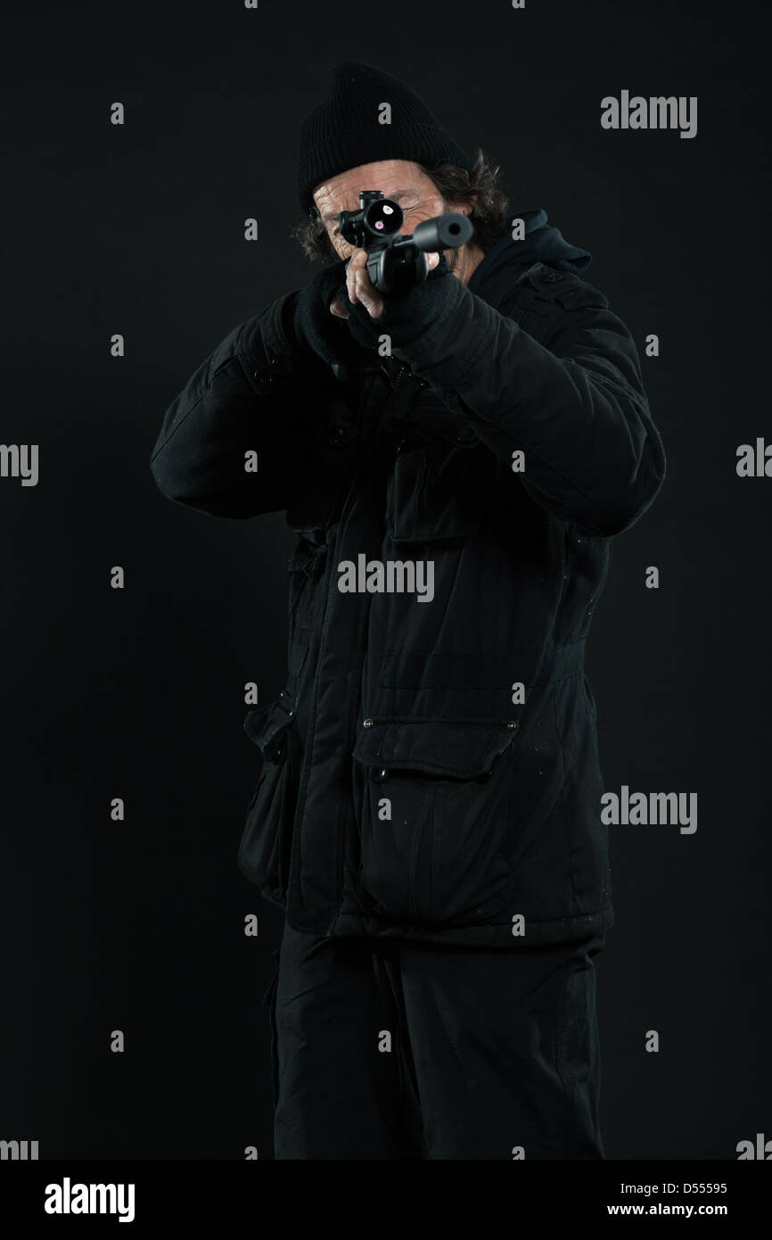 Sniper with beard in black holding gun. Studio shot Stock Photo - Alamy