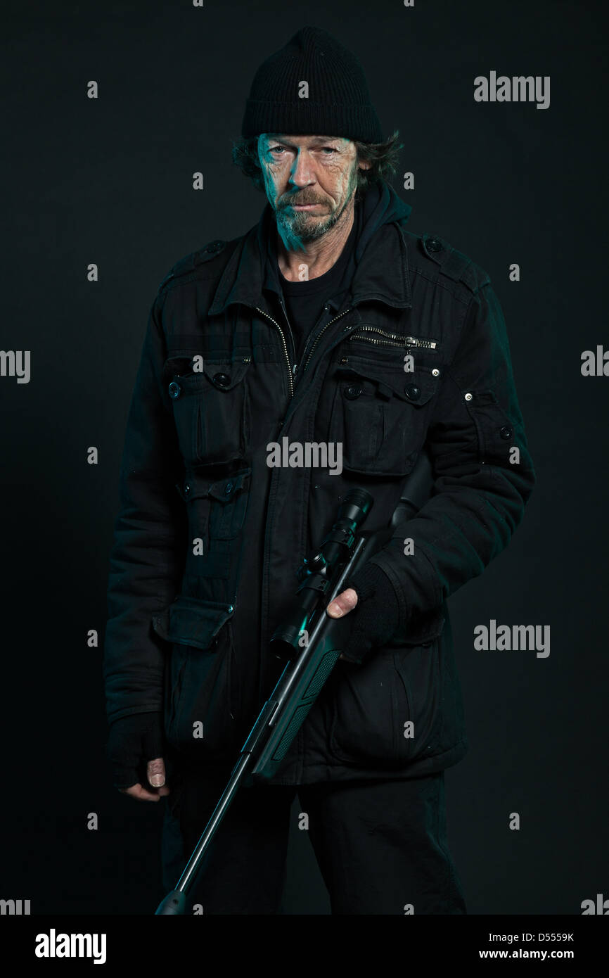 Sniper with beard in black holding gun. Studio shot Stock Photo - Alamy