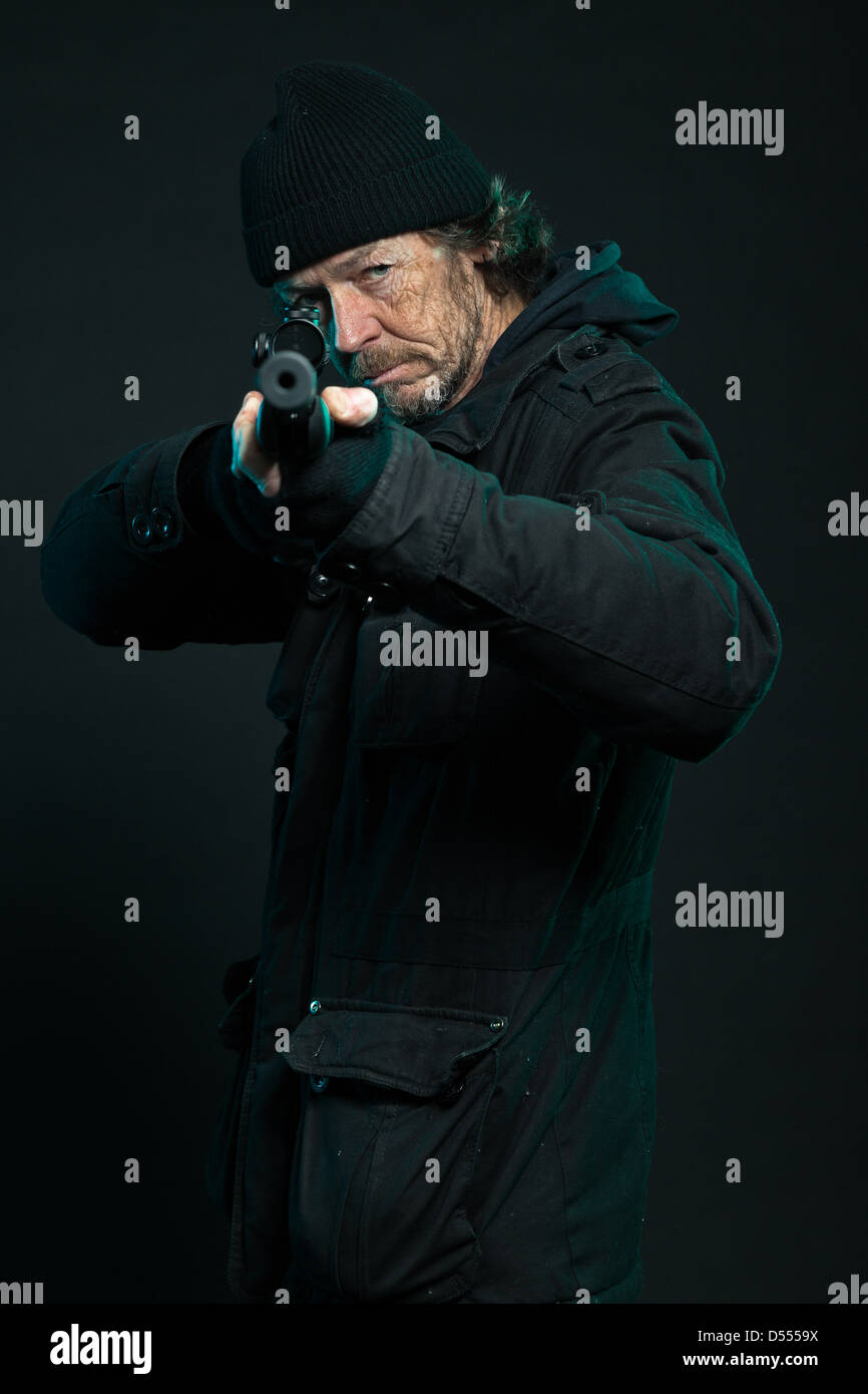 Sniper with beard in black holding gun. Studio shot Stock Photo - Alamy