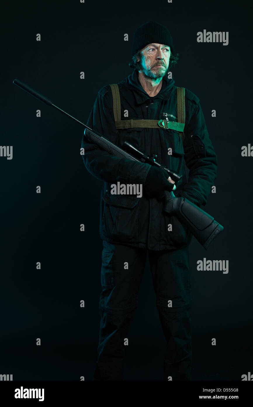 Sniper with beard in black holding gun. Studio shot Stock Photo - Alamy