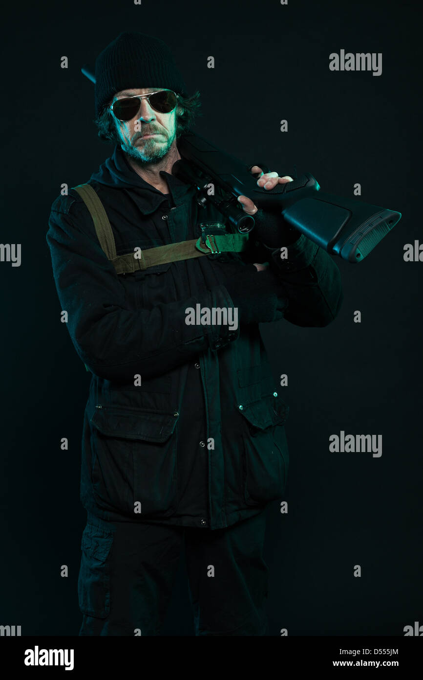 Sniper with beard in black holding gun. Studio shot Stock Photo - Alamy
