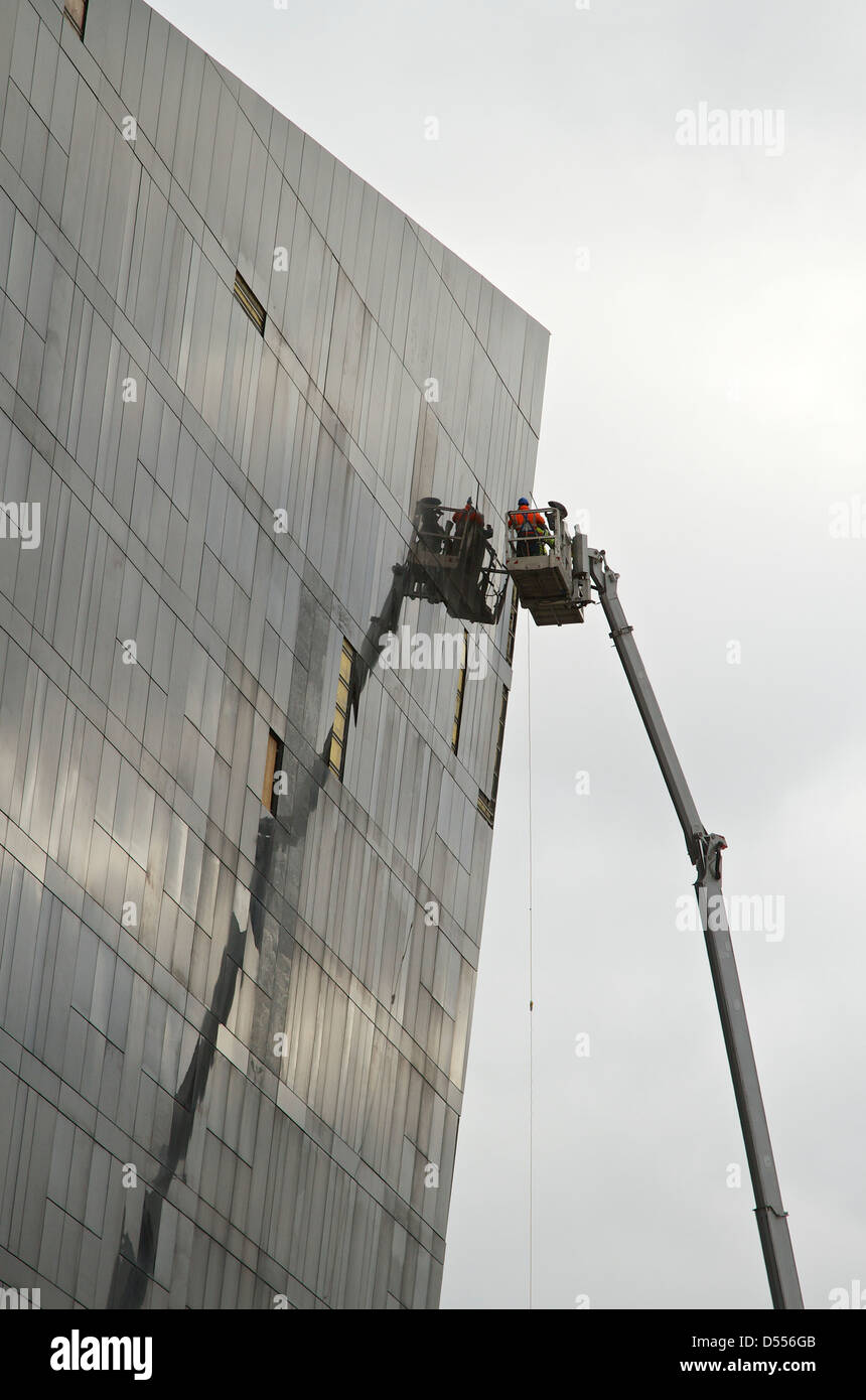 window cleaners on cherry picker crane washing tall glass sided ...