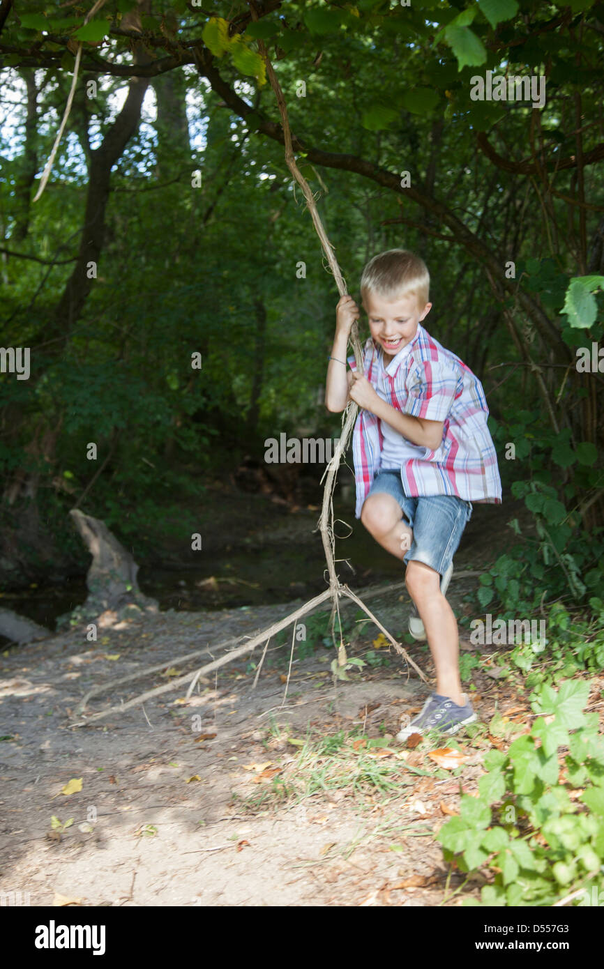 Boy playing on tree swing Stock Photo - Alamy
