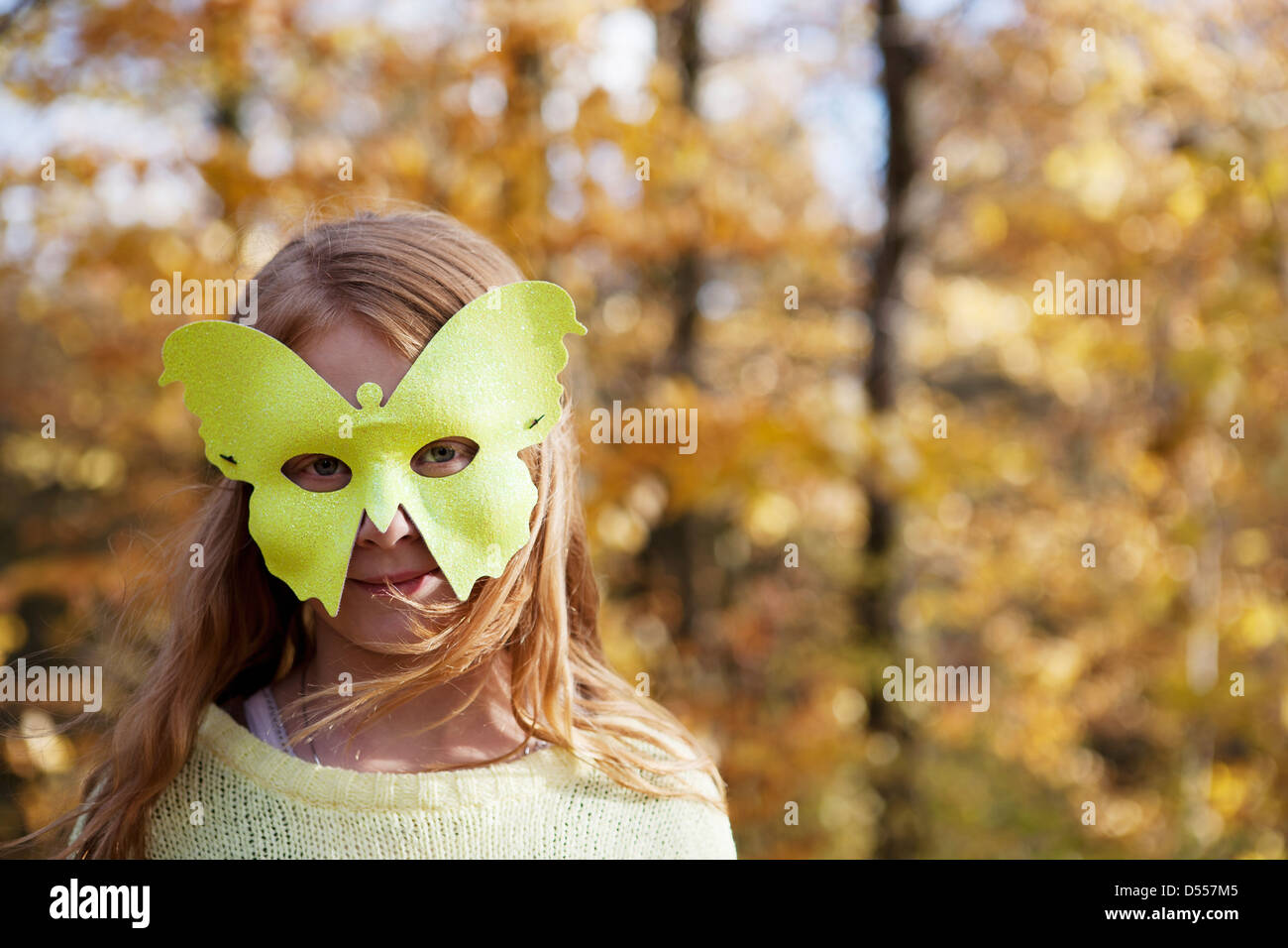 Girl wearing butterfly mask in park Stock Photo - Alamy