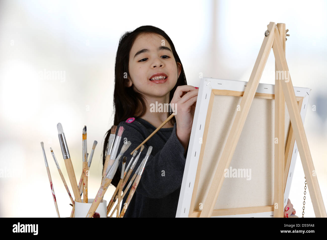 Girl painting a canvas while at school Stock Photo - Alamy