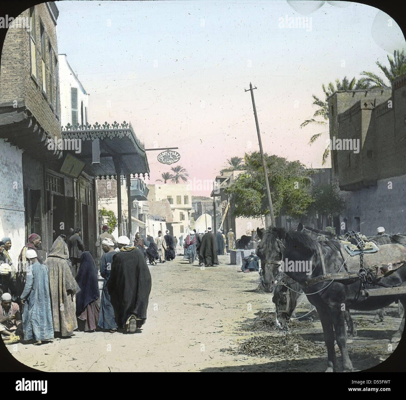 A hand-tinted photograph of a street scene in Assiut, Egypt, capturing ...