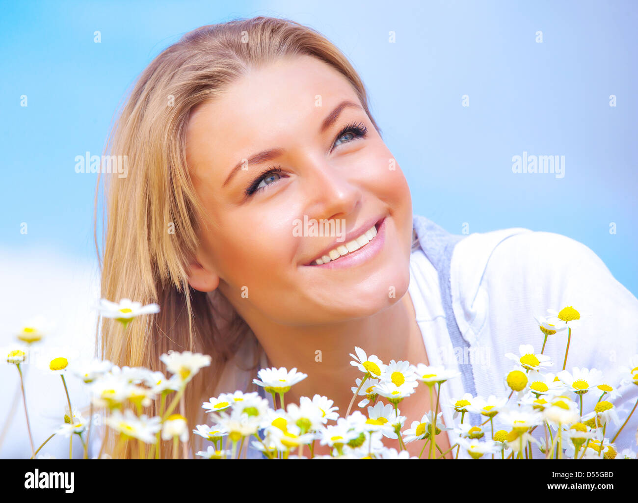 Young beautiful girl laying on the daisy flowers field, outdoor ...