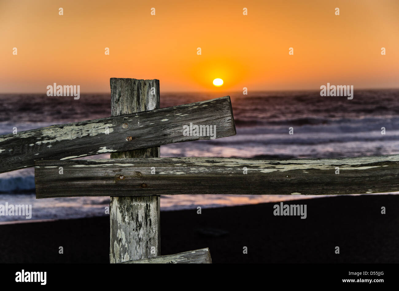 Summer sunset on a California beach with a wooden fence in the ...