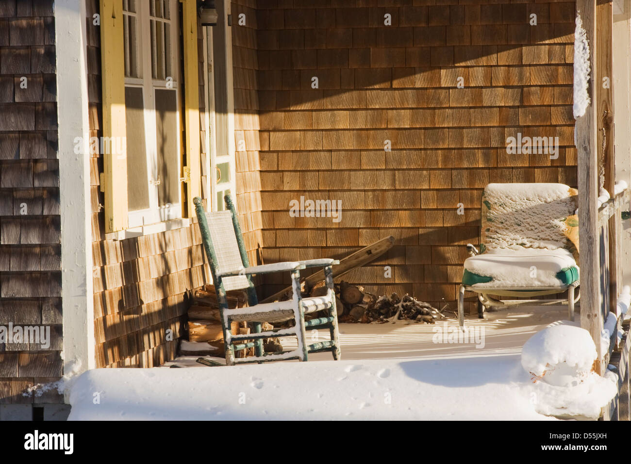 Rocking chair and snow on front porch of vacant cottage in winter Stock ...