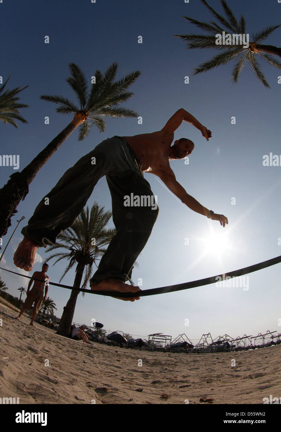 A young man practice slackline on the beach. Slacklining is a practice ...