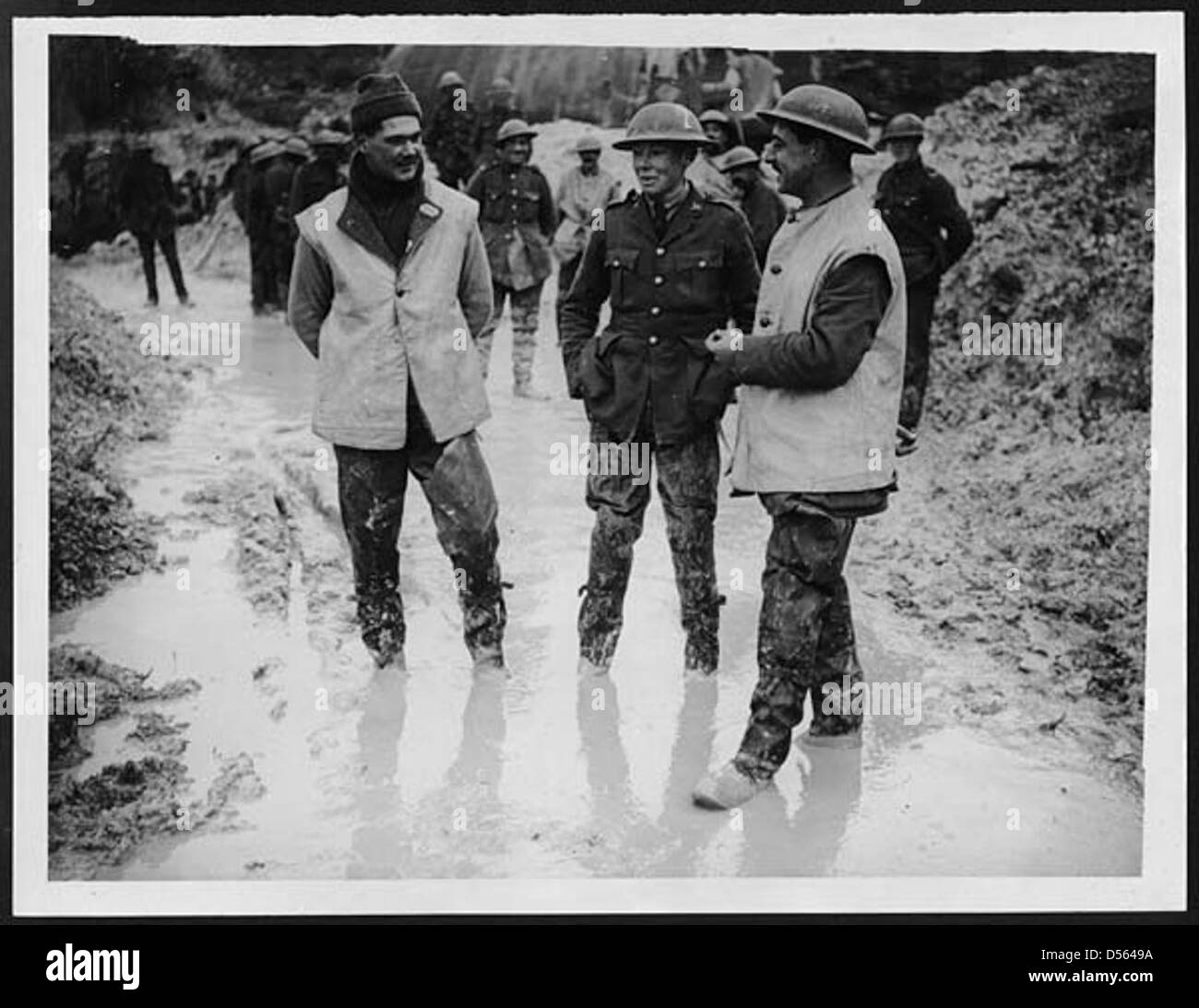 Three military officers, wearing trench waders, having a conversation ...