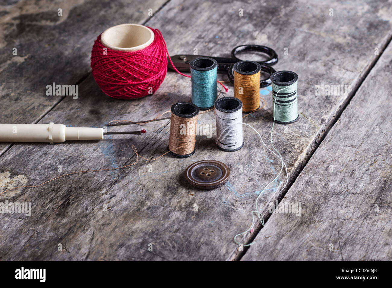 Many bobbin of thread with needle and button on table Stock Photo - Alamy