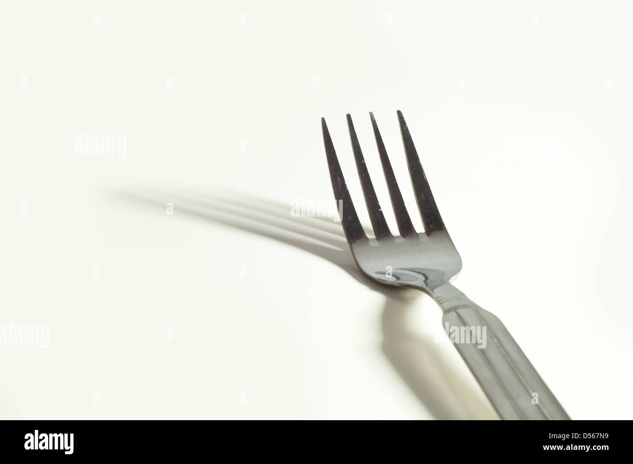metallic fork and her shadow on the white background Stock Photo - Alamy
