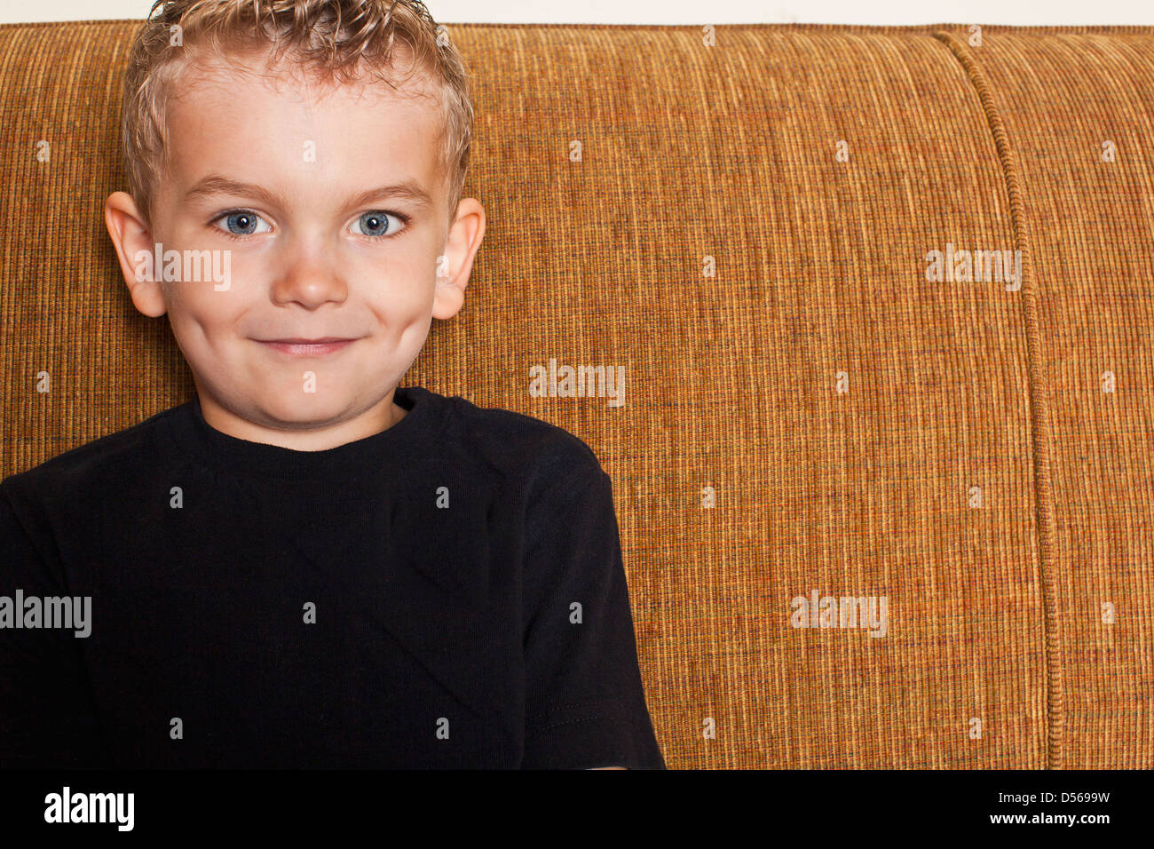 Smiling Caucasian boy sitting on sofa Stock Photo - Alamy