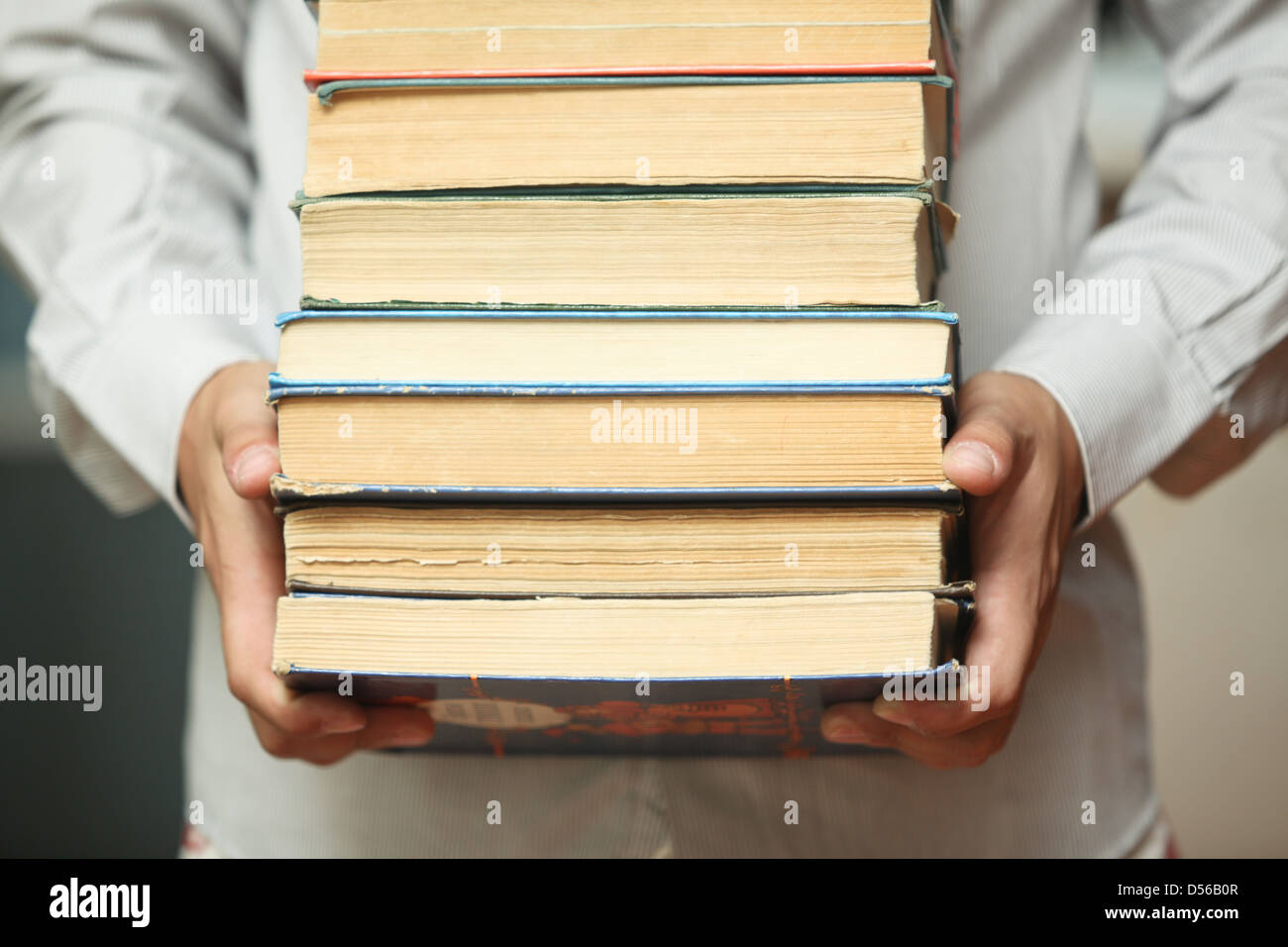 Guy in a shirt holding a stack of old books Stock Photo - Alamy