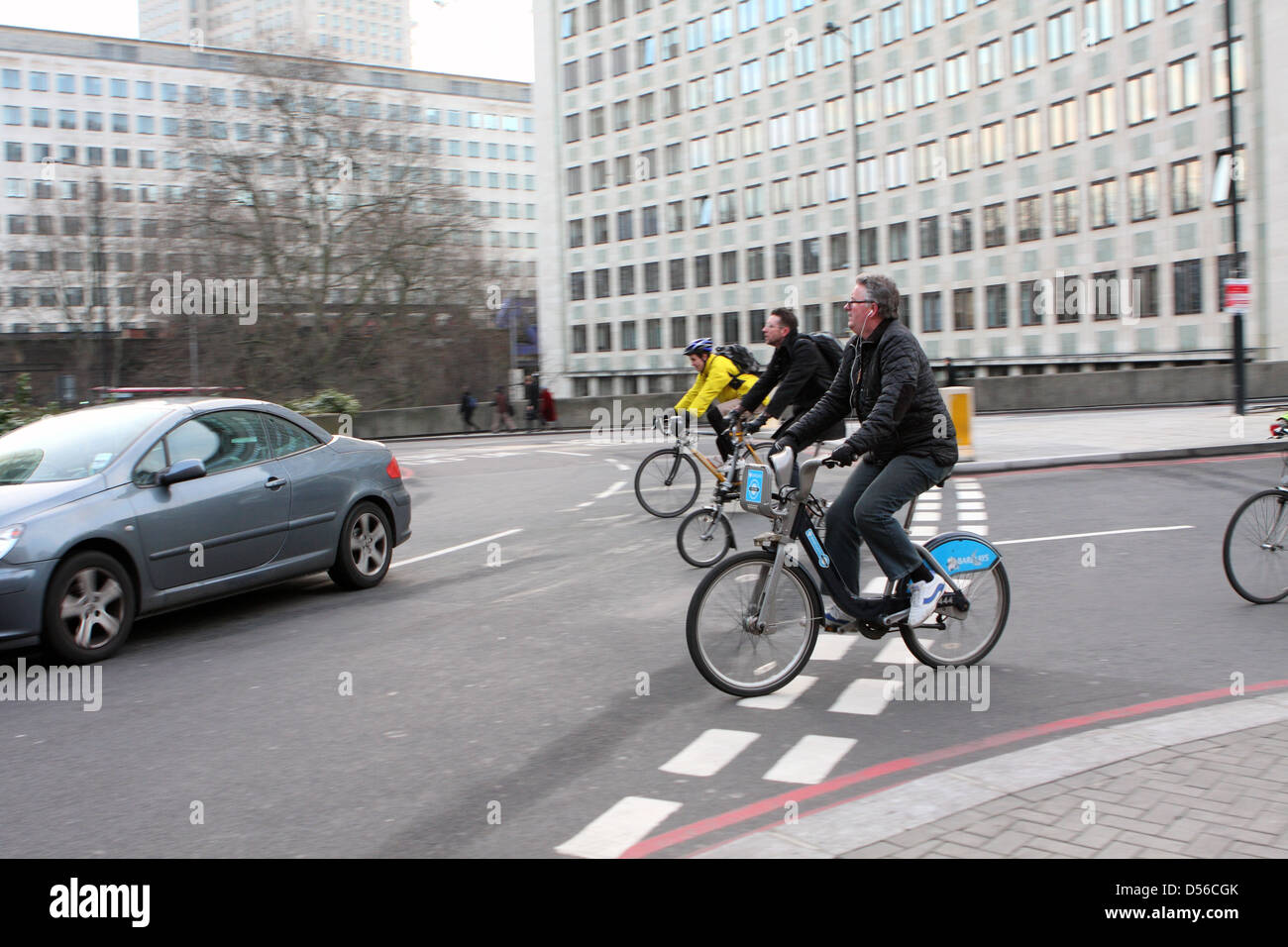 Cyclists entering a roundabout in London, England as a car already on ...