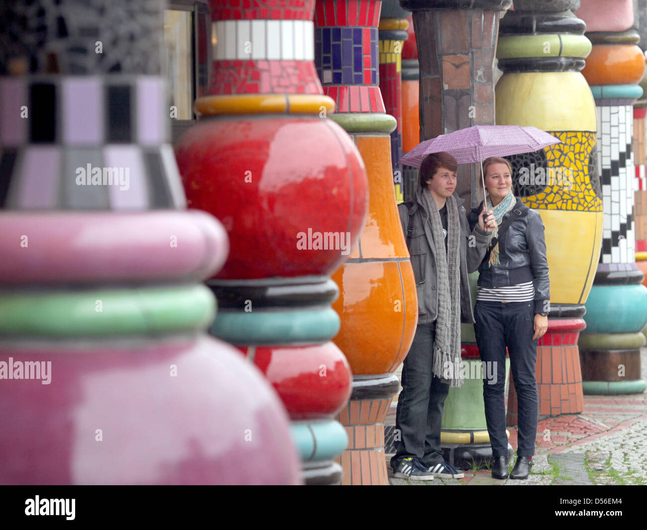 Passersby seek shelter from the rain under some colourful columns in ...