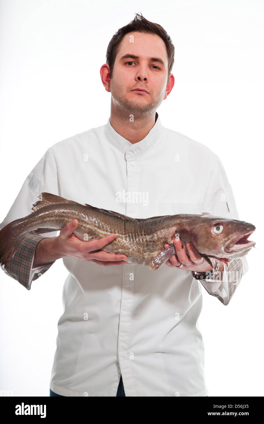 Young male cook with white jacket holding a big fish isolated on white ...