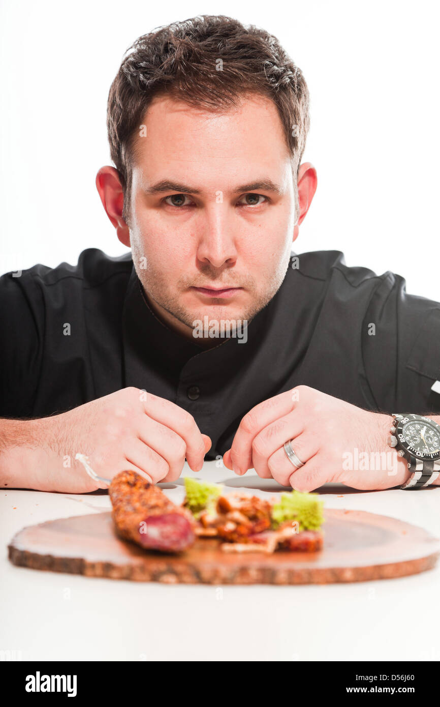 Young male cook with black jacket preparing raw ingredients isolated on ...