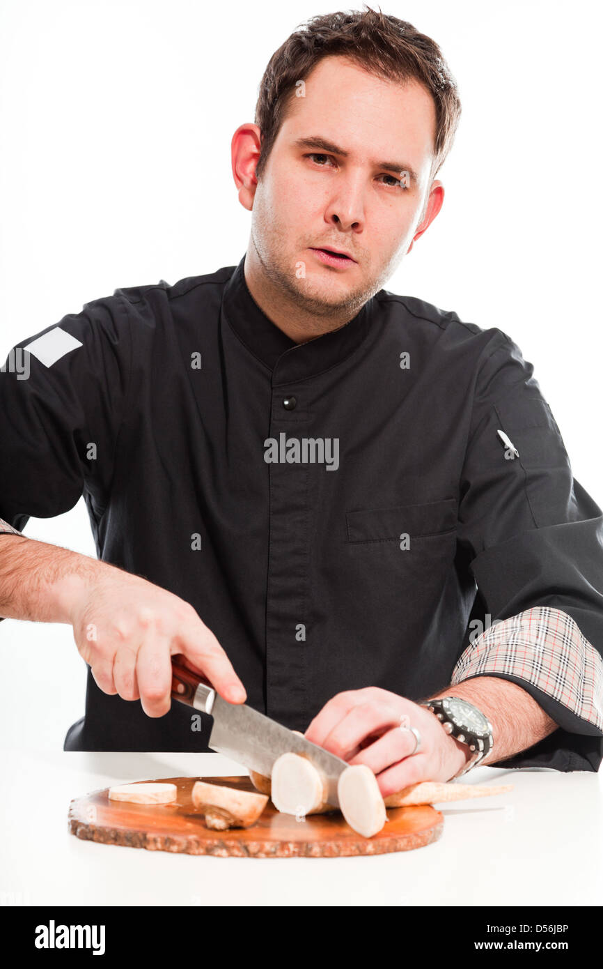 Young male cook with black jacket preparing raw ingredients isolated on ...