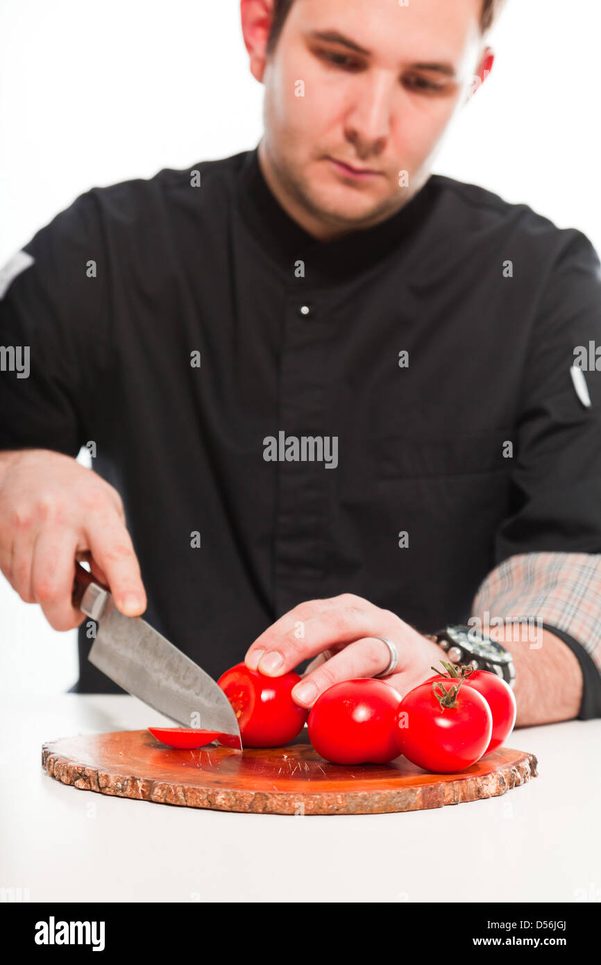 Young male cook with black jacket preparing raw ingredients isolated on ...