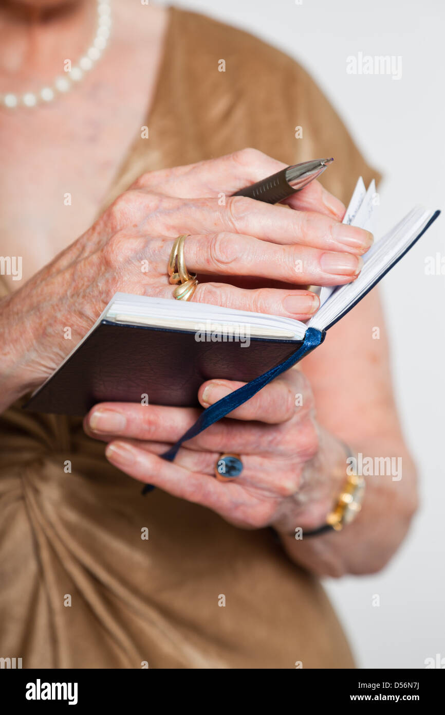 Hands of senior woman holding agenda. Studio shot on grey background ...