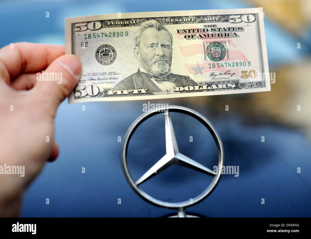 ILLUSTRATION - A Dollar bill is pictured behind a Mercedes star in ...