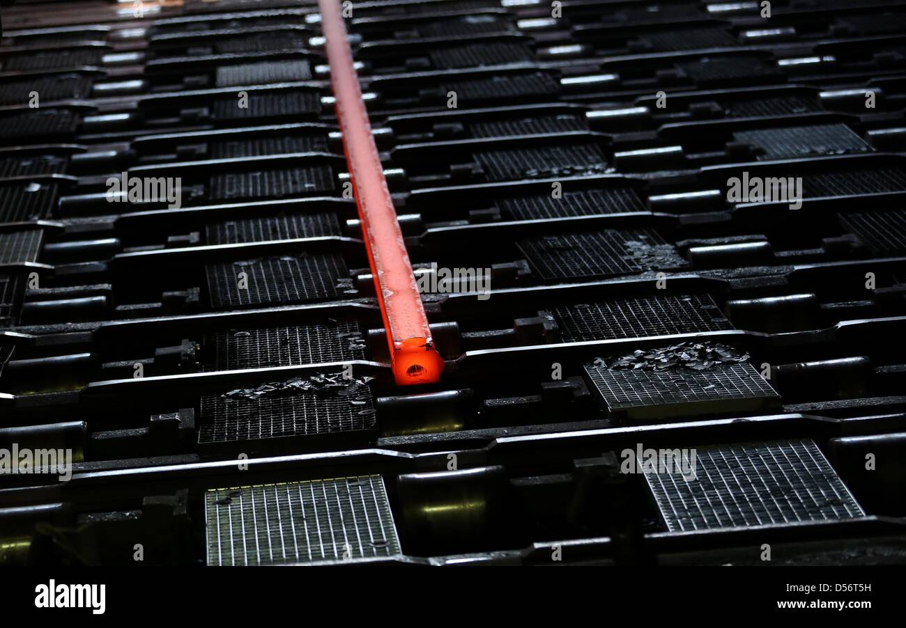 A piece of gleaming steel is transported along a conveyor belt at the ...