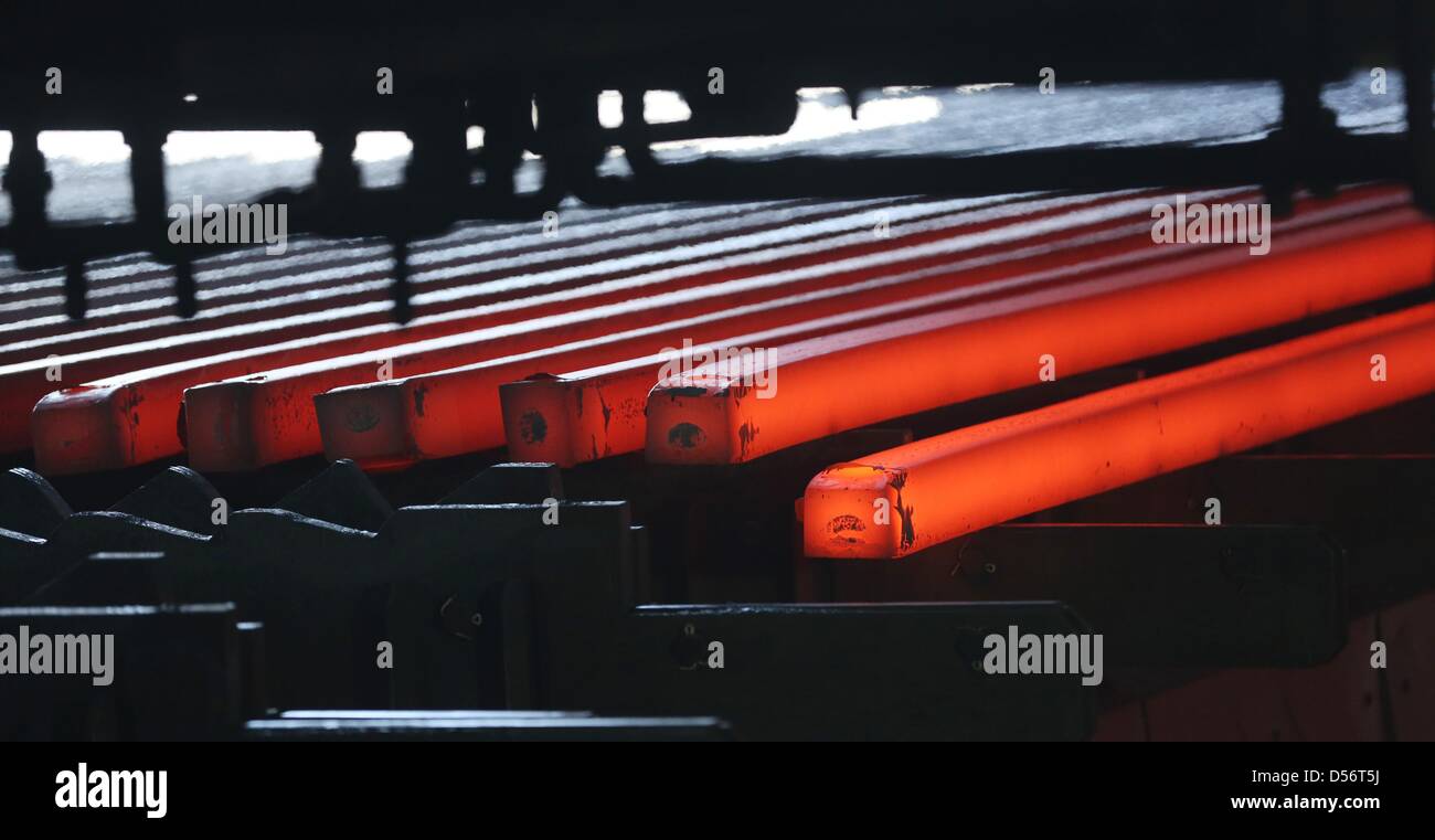 A piece of gleaming steel is transported along a conveyor belt at the ...