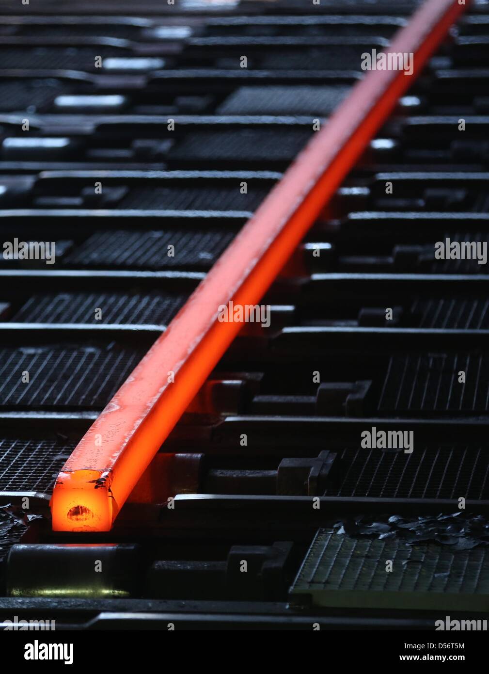 A piece of gleaming steel is transported along a conveyor belt at the ...