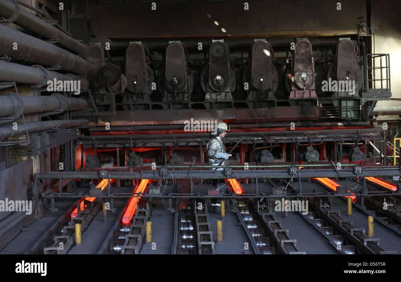 A caster observes pieces of gleaming steel being transported along a ...