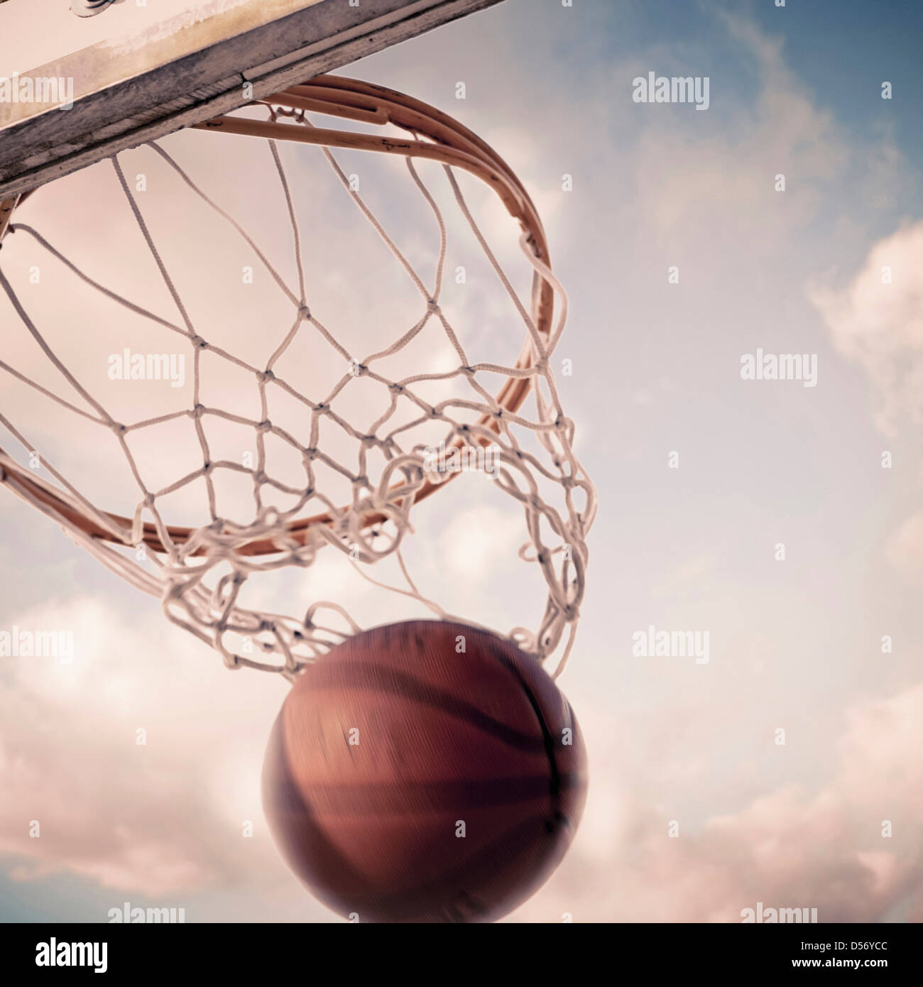 Basketball falling through hoop on court Stock Photo - Alamy