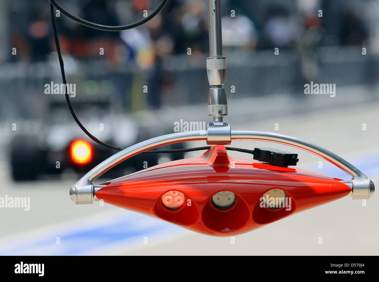 A Formula One racecar drives passed the pit stop light of Ferrari ...