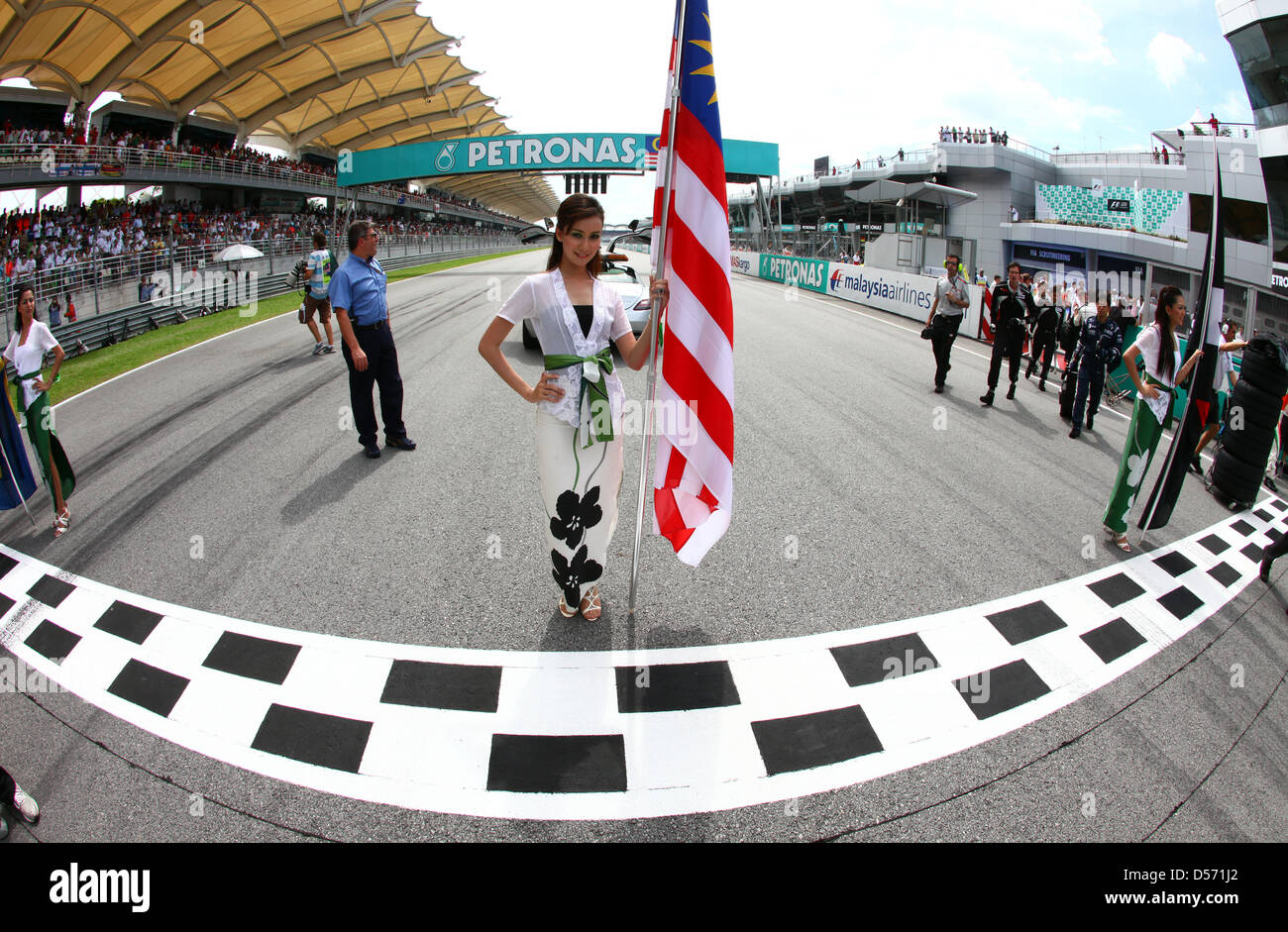 A grid girl poses with a Malaysian flag in the starting line up ahead ...