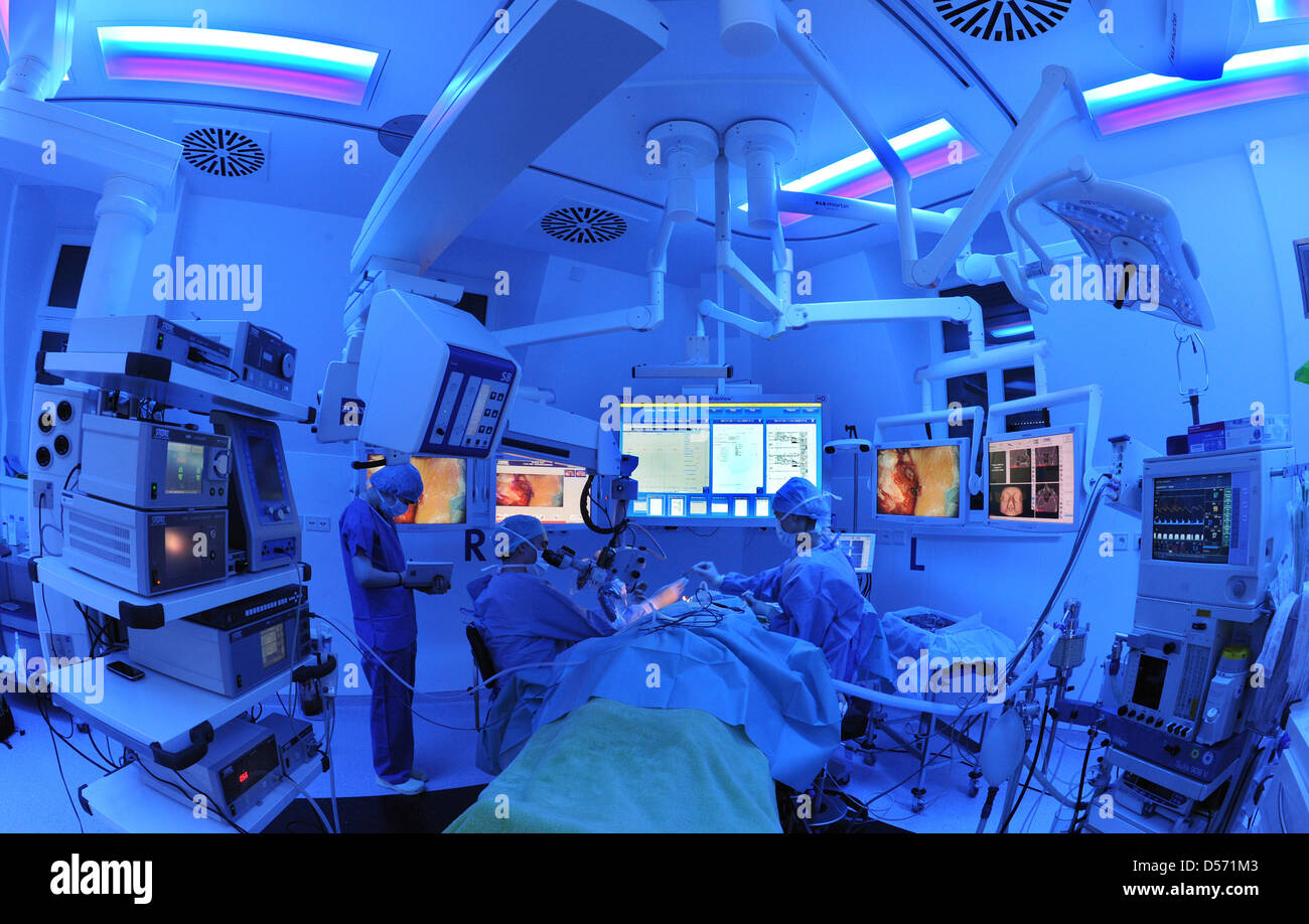 Surgeon Gero Strauss (R) operates on a patient's ear under red light in ...