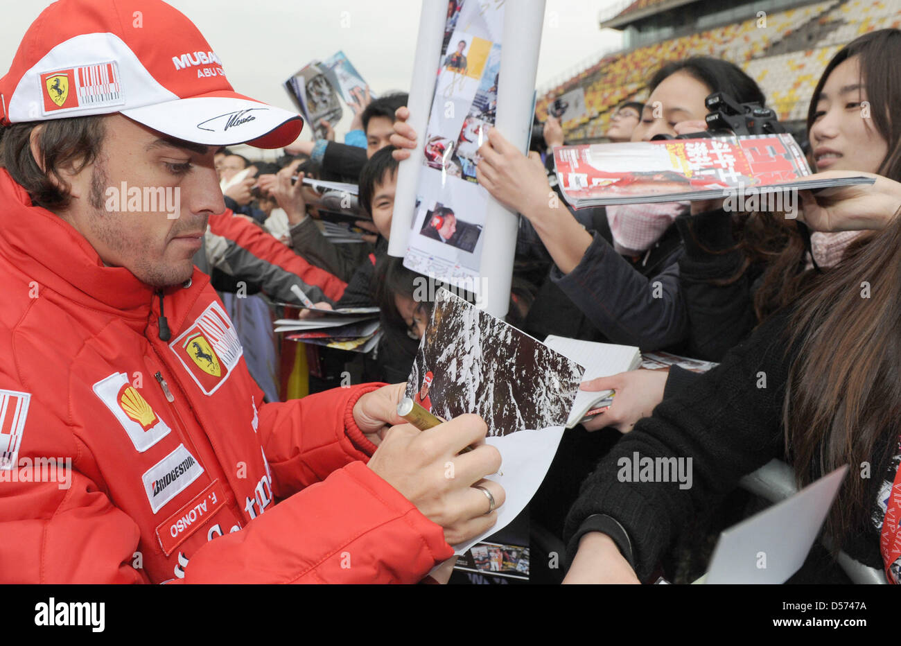 Spanish Formula One driver Fernando Alonso of Ferrari (L) signs ...