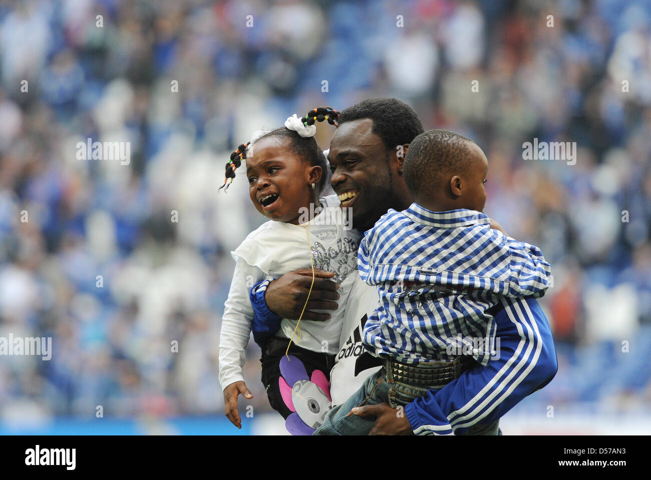 Schalke's Gerald Asamoah walks over the pitch with his crying children ...