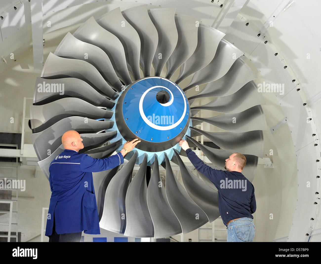 Two staff members check engine blades in a vacuum chamber in the ...
