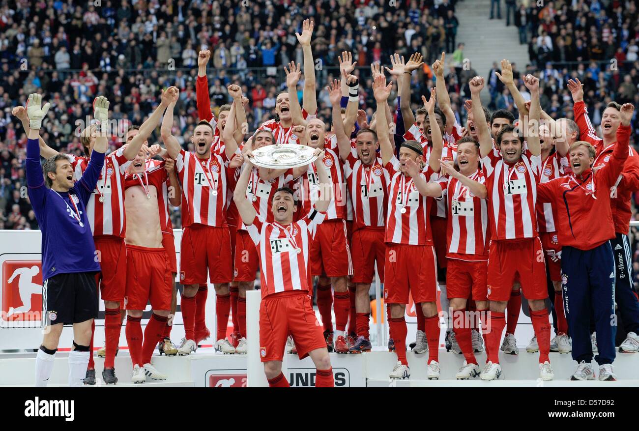 Bayern Munich's skipper Mark van Bommel (C) lifts the trophy for ...