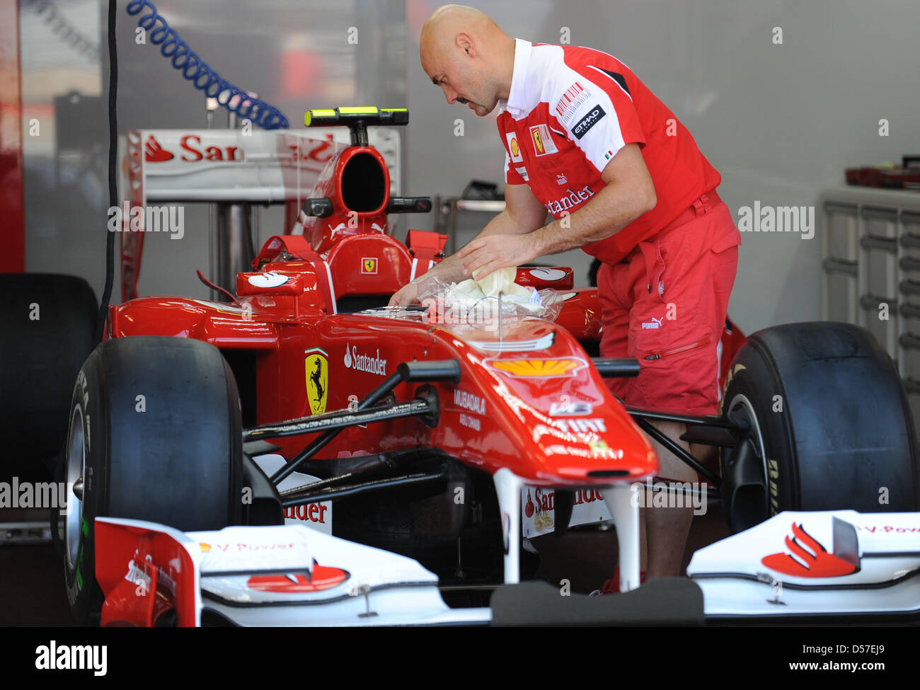A mechanic of Scuderia Ferrari works on the race car of Spanish driver ...