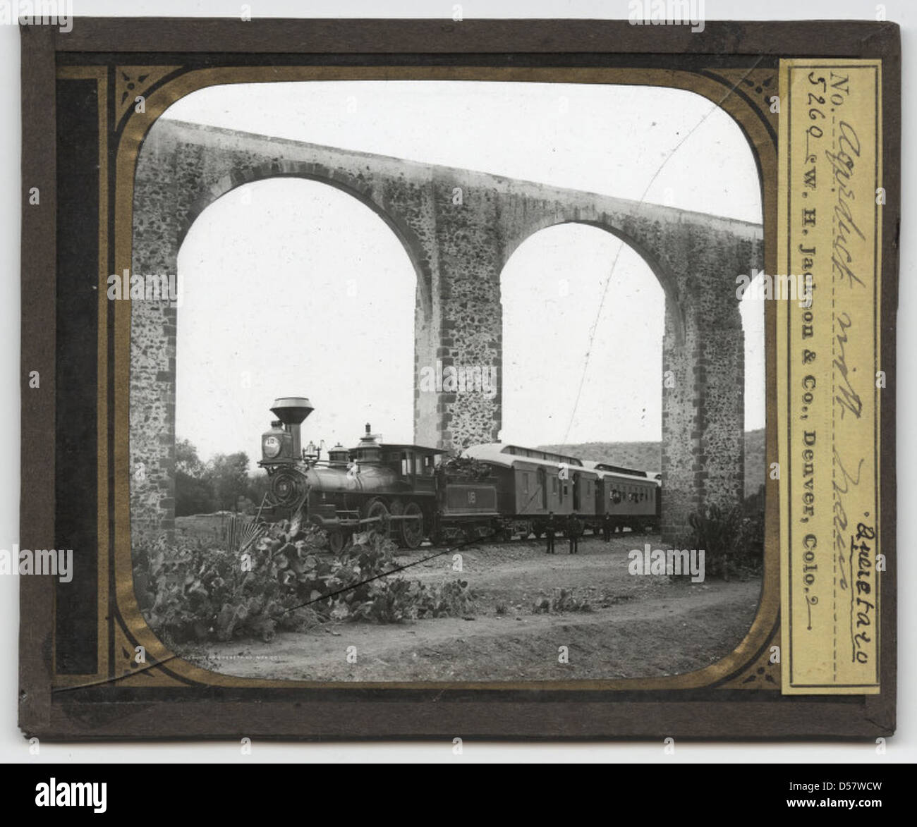 This photograph features a train crossing an aqueduct in Queretaro ...