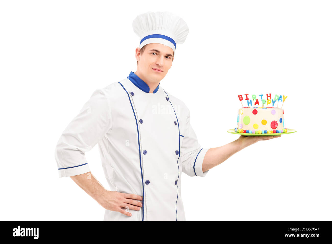 Young male chef in a uniform holding a decorated birthday cake isolated ...