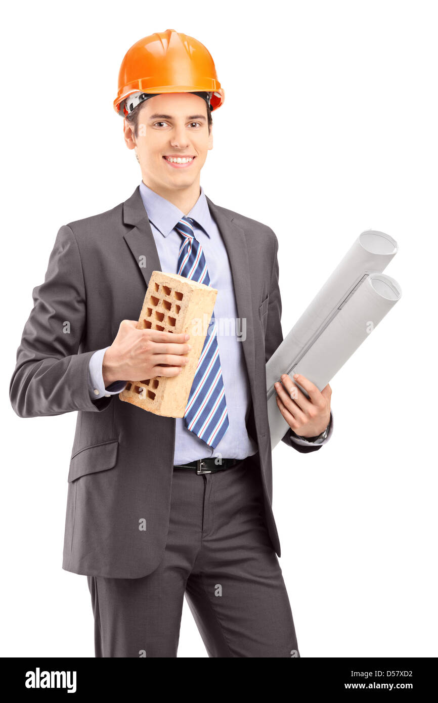 Young male engineer holding a brick and a blueprint isolated on white ...