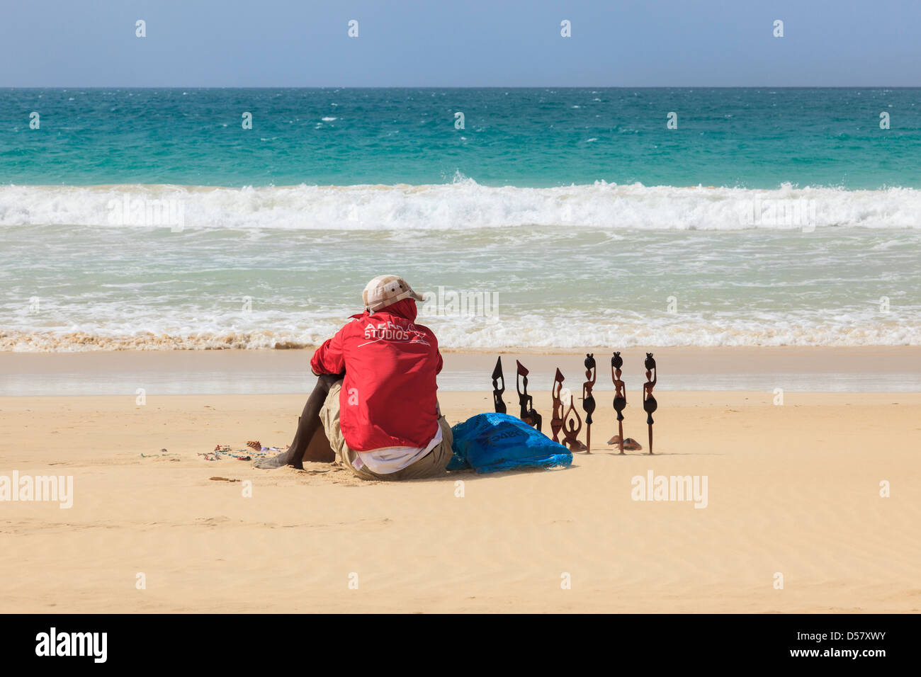 Local young black man sitting in hot sun displaying African carvings to ...
