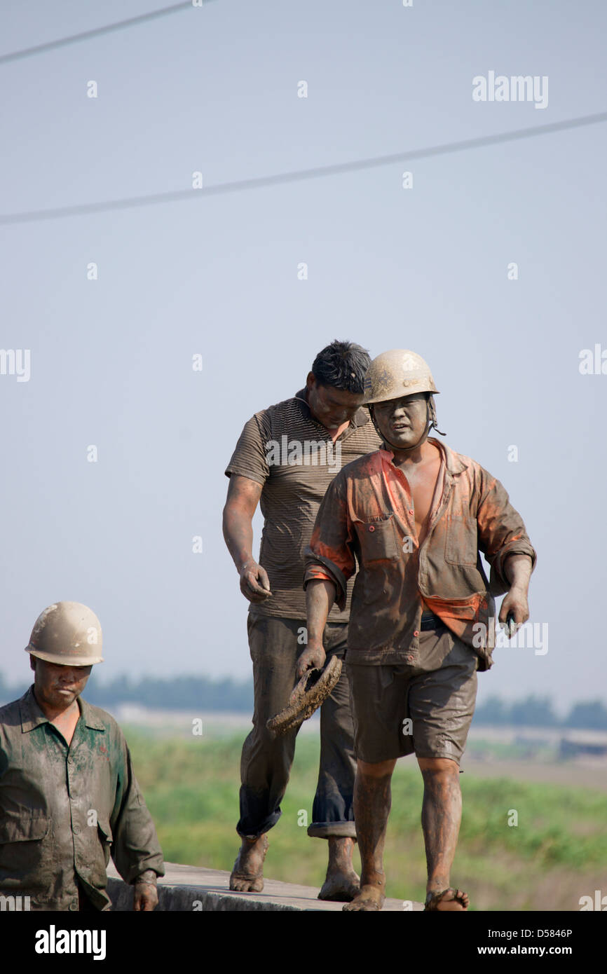 Muddied workers walking after setting up a sentiment diversion pipe ...